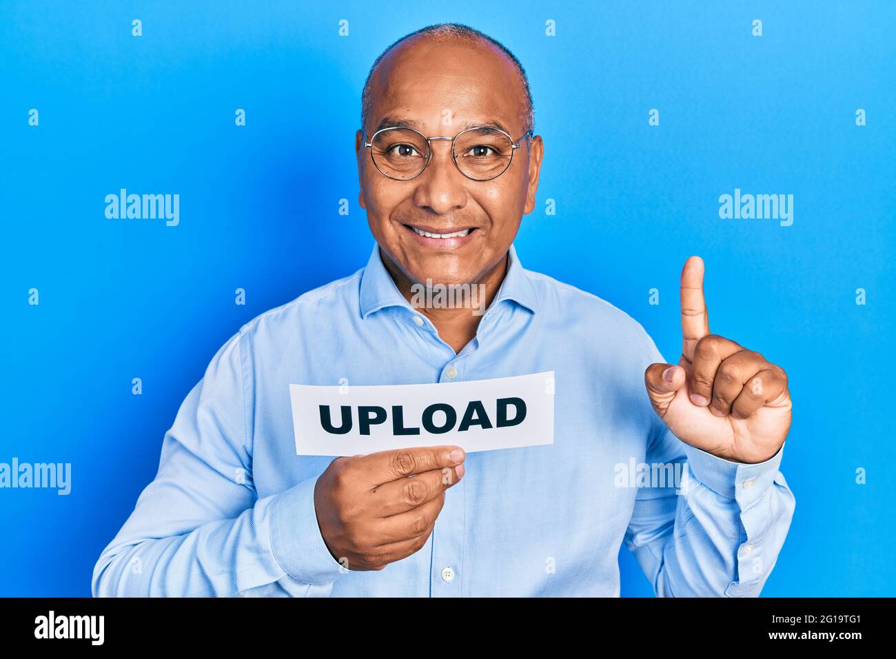 Middle age latin man holding upload paper message smiling with an idea ...