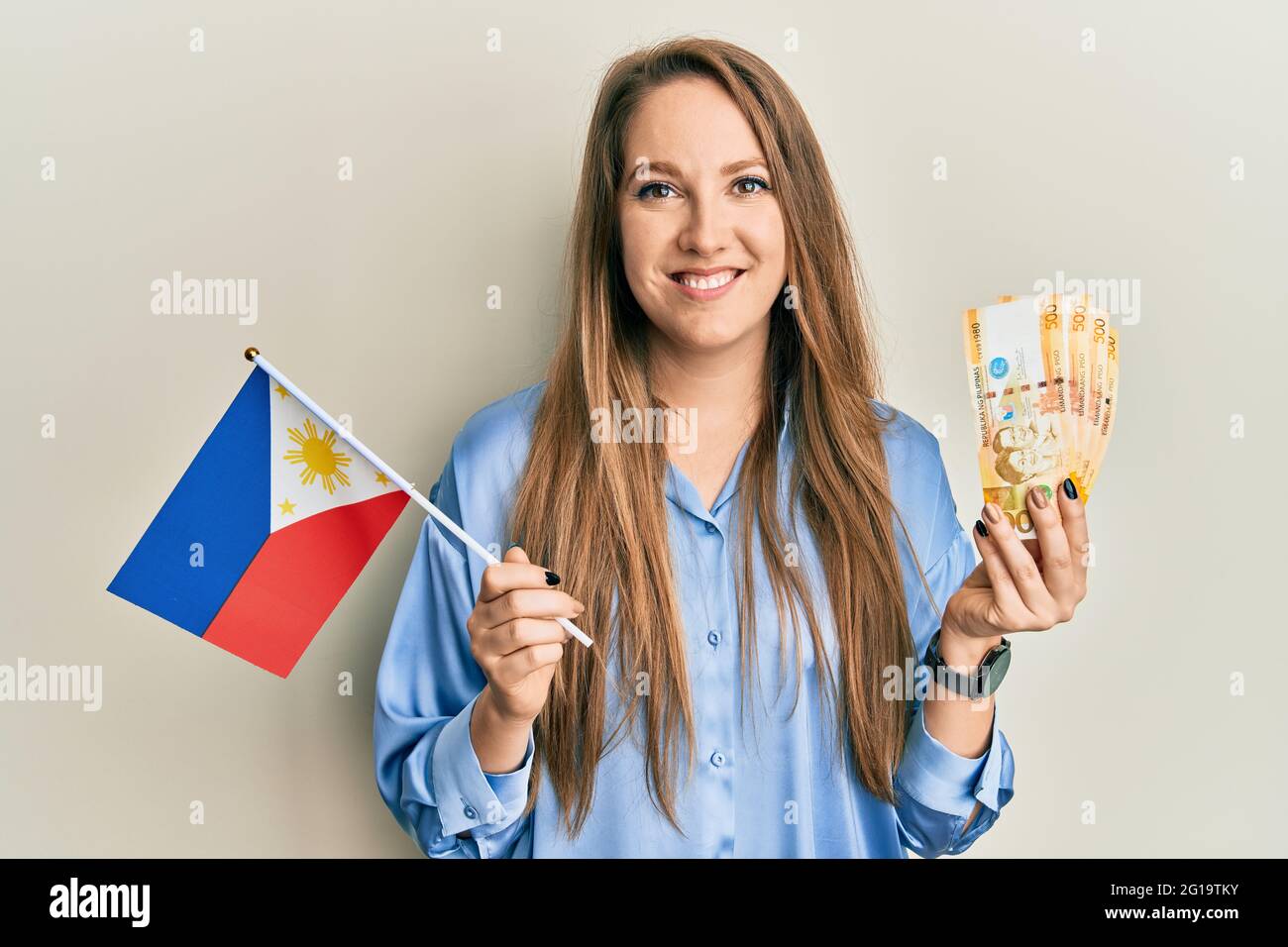Young blonde woman holding philippine flag and philippines pesos ...