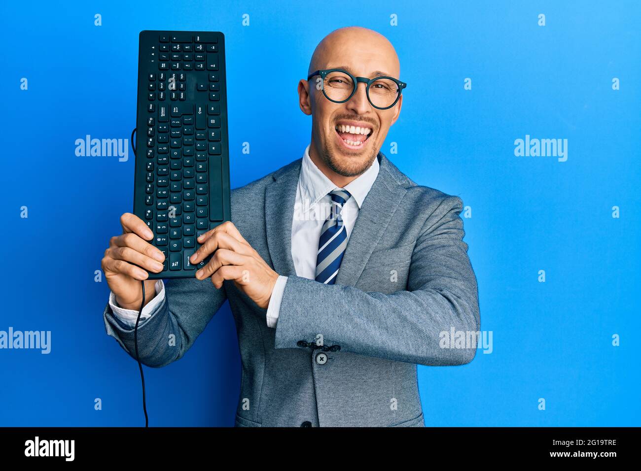 Bald man with beard holding keyboard smiling and laughing hard out loud ...