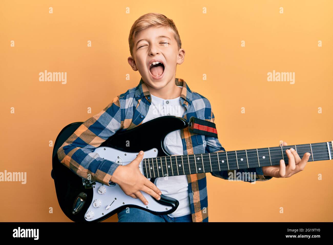 Little caucasian boy kid playing electric guitar smiling and laughing ...