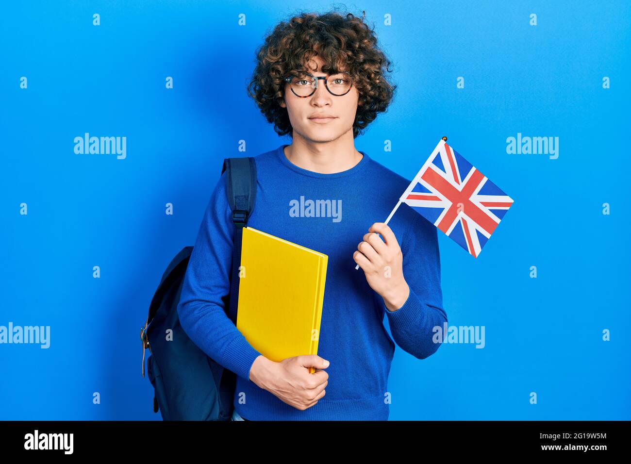 Handsome young man exchange student holding uk flag relaxed with ...