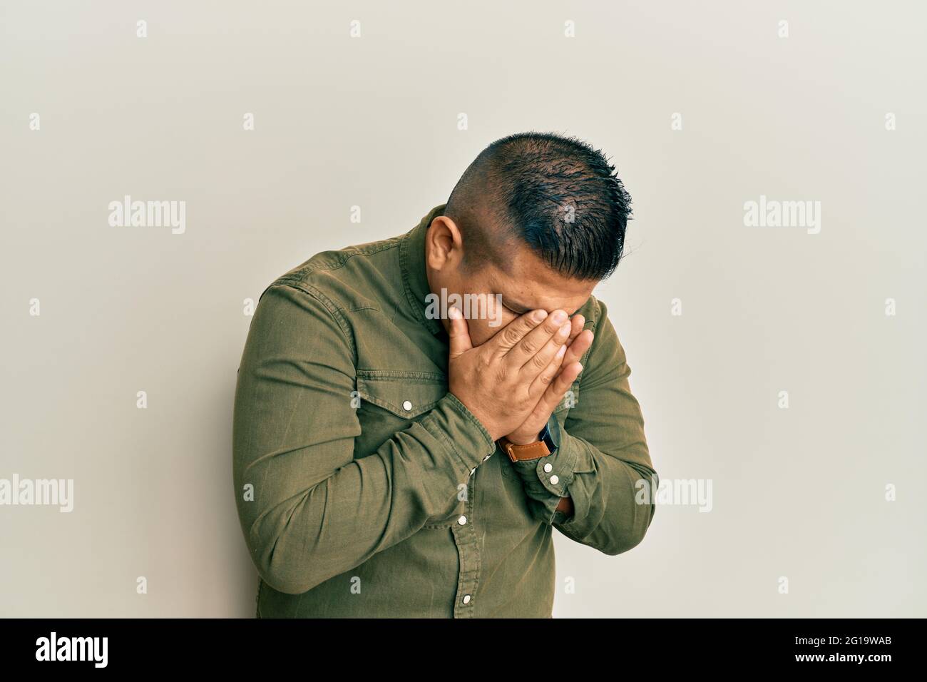 Young latin man wearing casual clothes with sad expression covering ...
