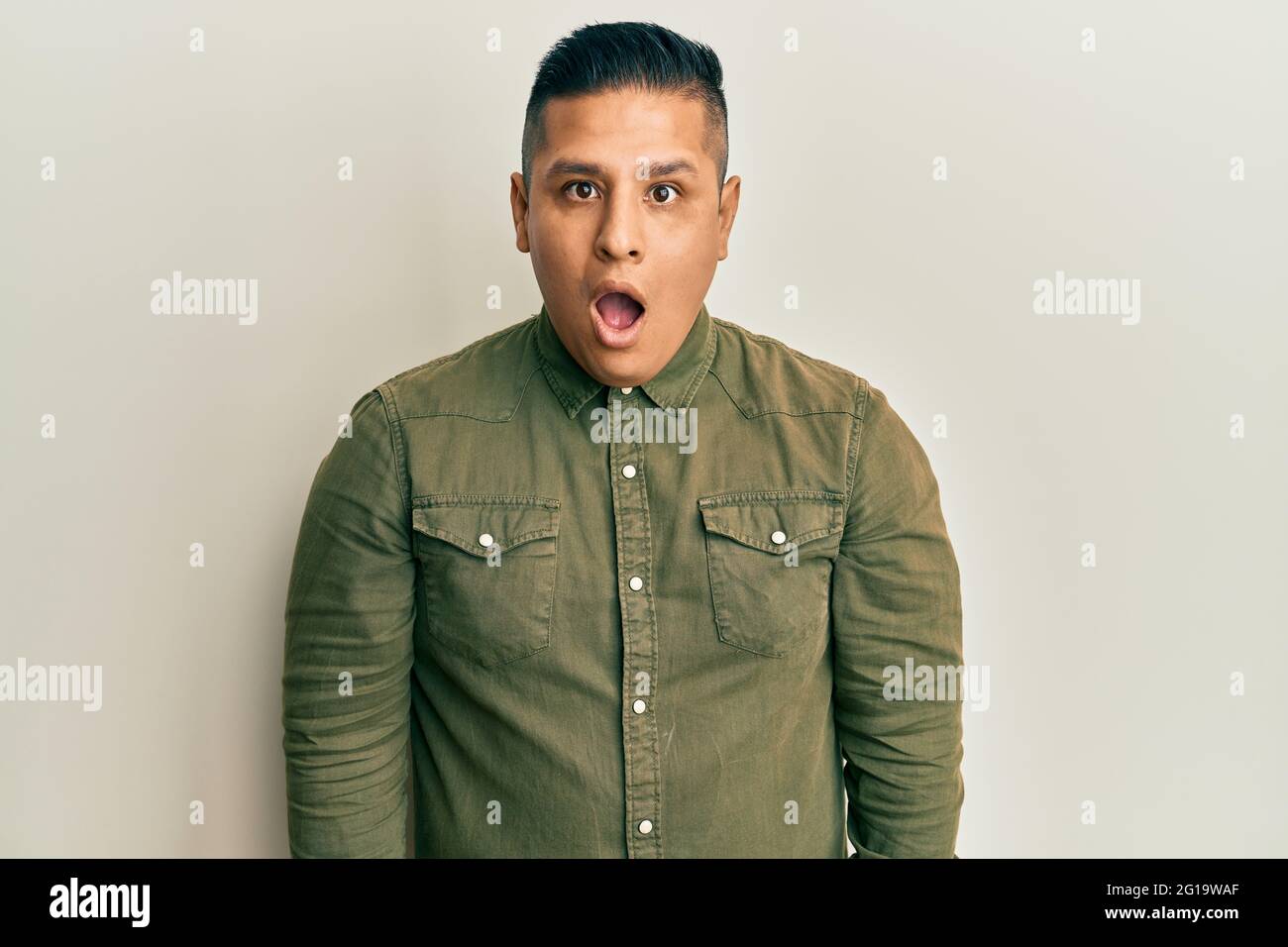 Young latin man wearing casual clothes afraid and shocked with surprise ...