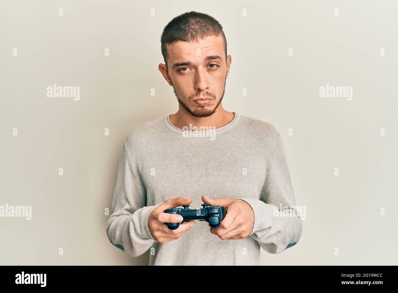 Hispanic young man playing video game holding controller depressed and ...