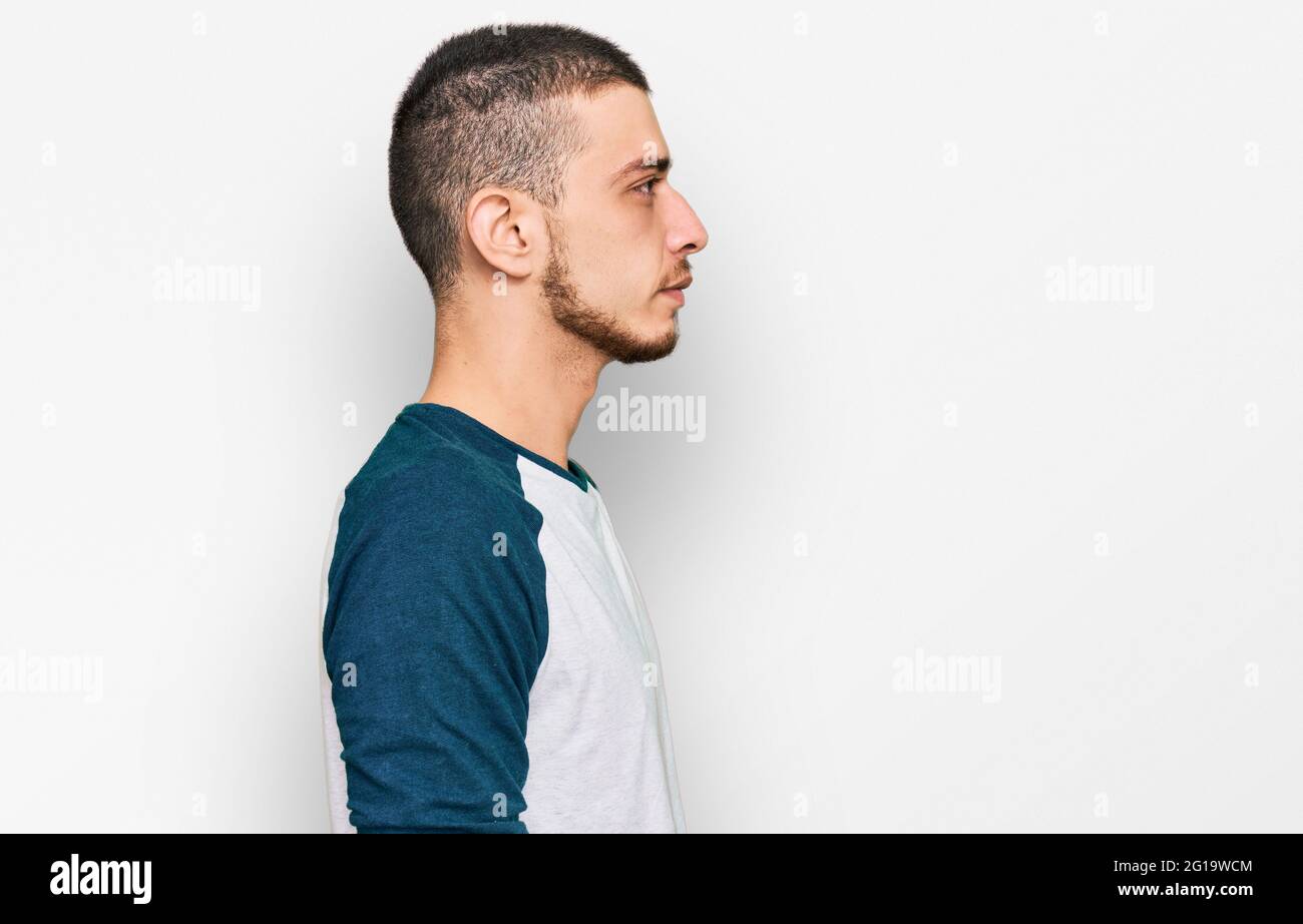 Hispanic young man wearing casual clothes looking to side, relax ...
