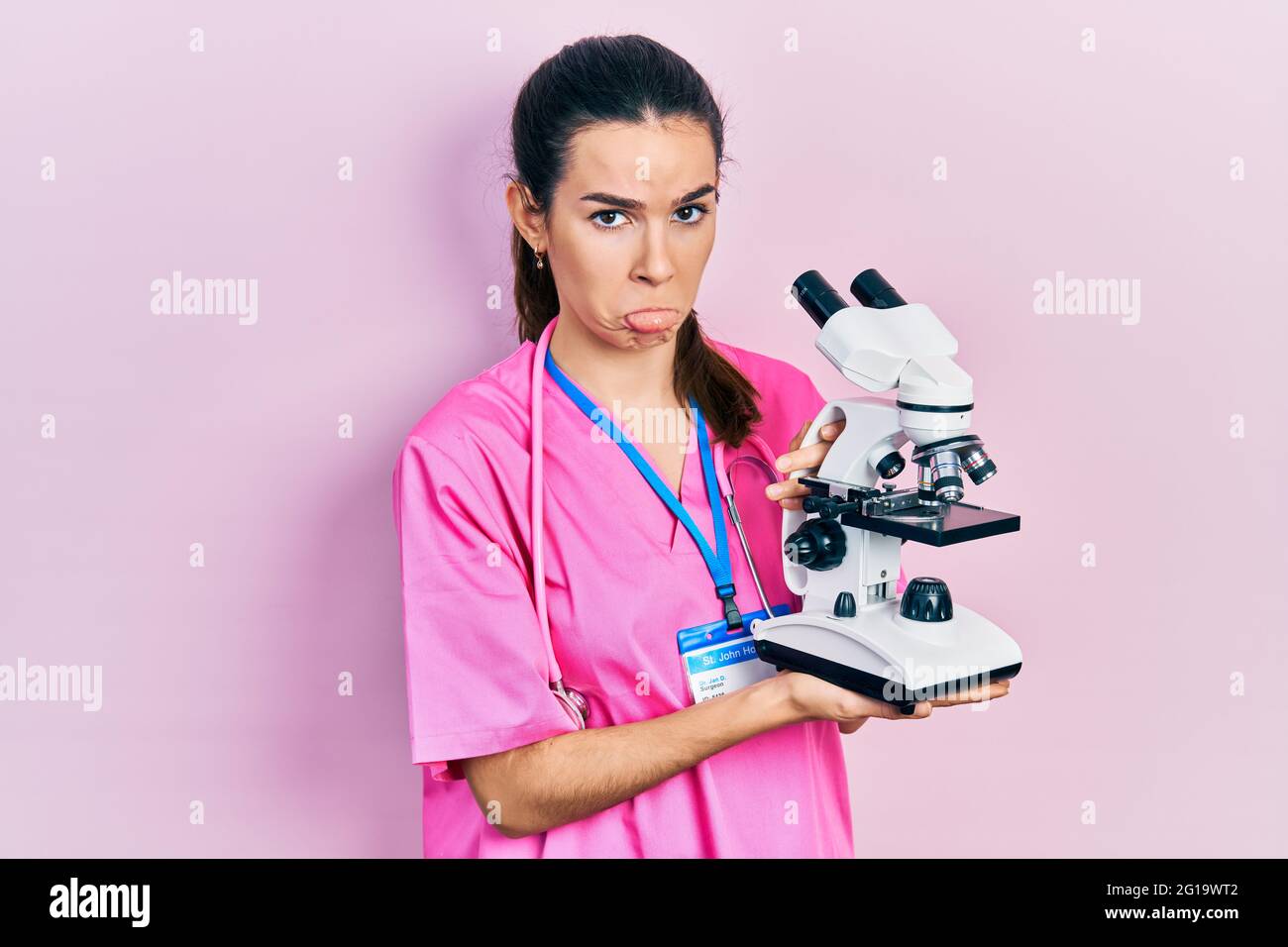 Young brunette woman holding microscope depressed and worry for ...