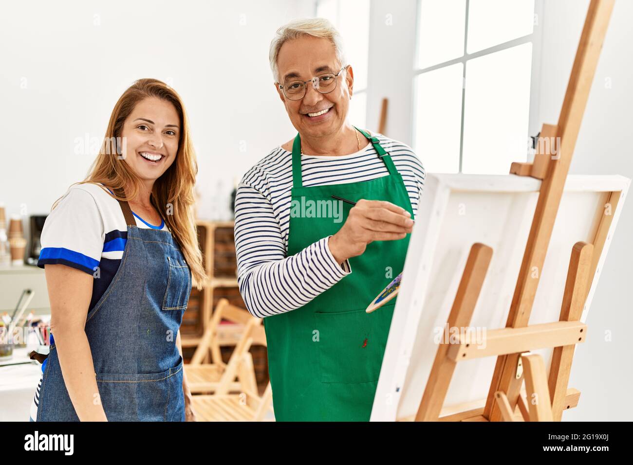 Middle age paint teacher and student smiling happy painting at art ...