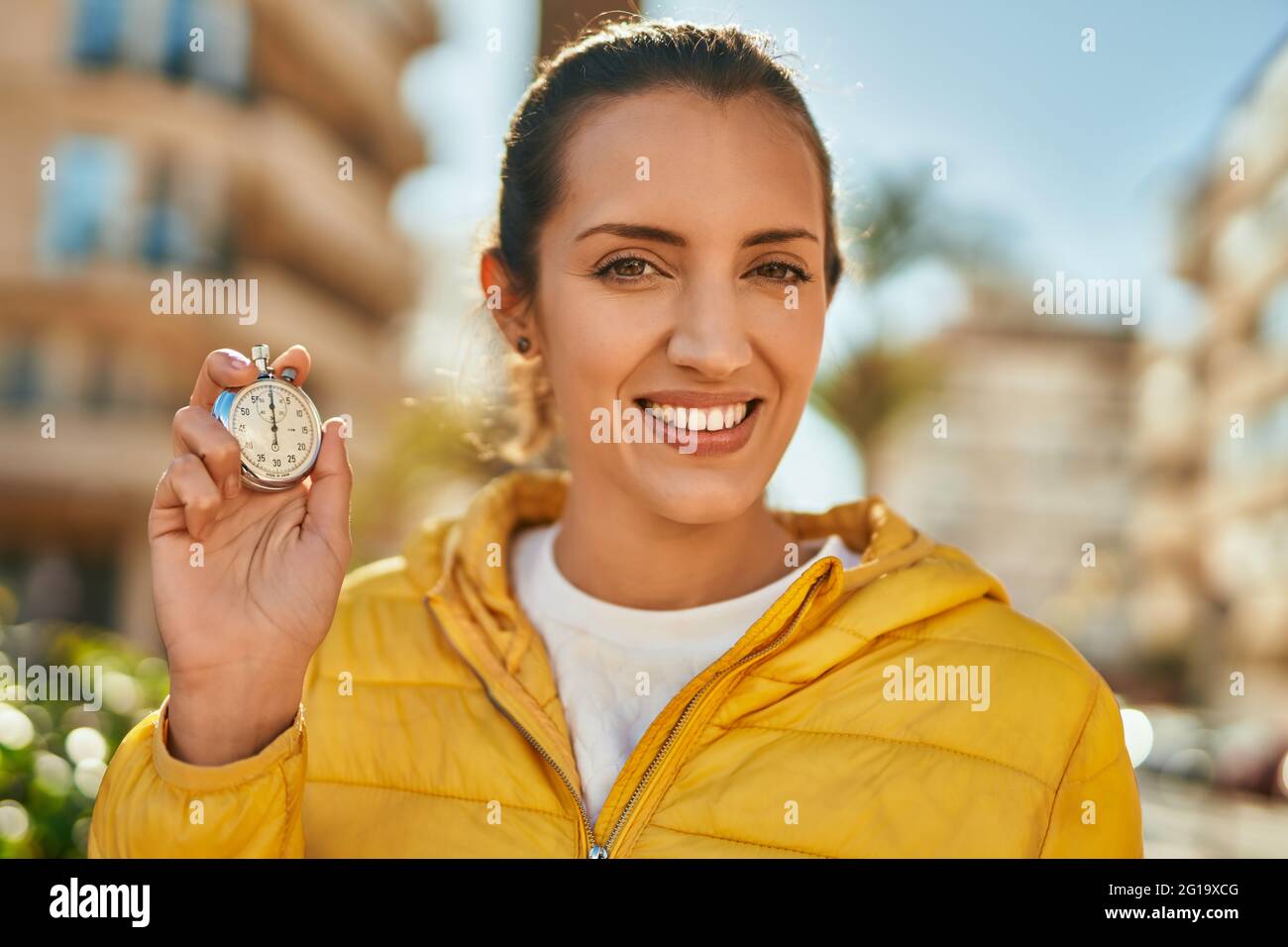 Young hispanic girl smiling happy holding stopwatch at the city Stock ...