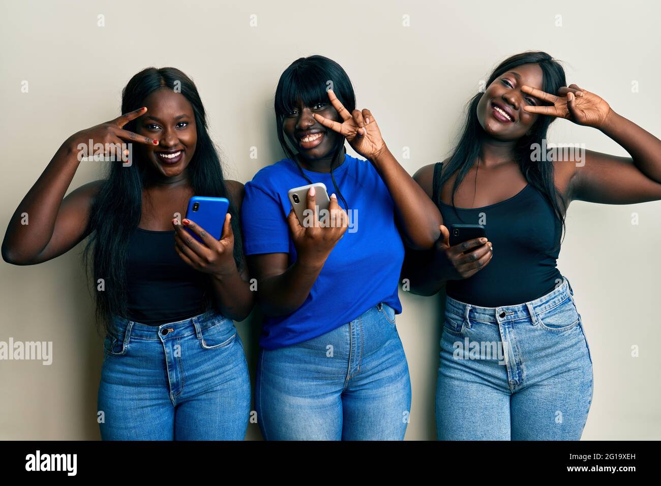 Three young african american friends using smartphone doing peace ...