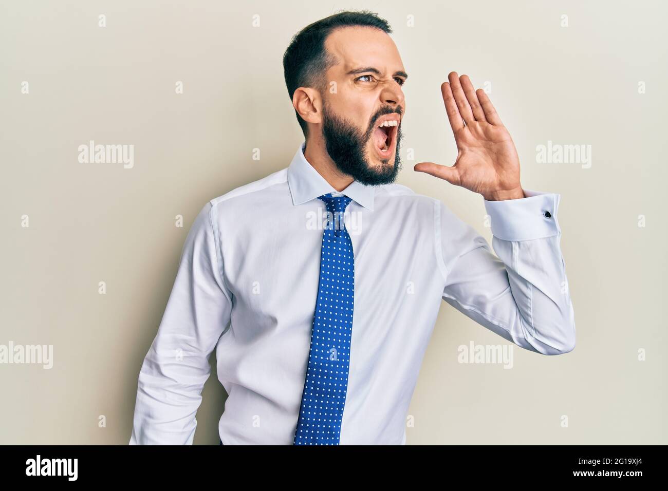 Young man with beard wearing business tie shouting and screaming loud ...
