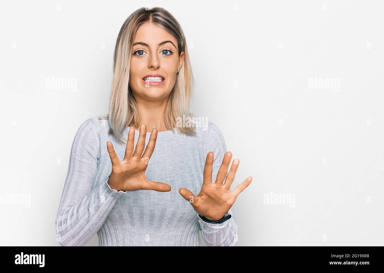 Beautiful blonde woman wearing casual clothes afraid and terrified with ...