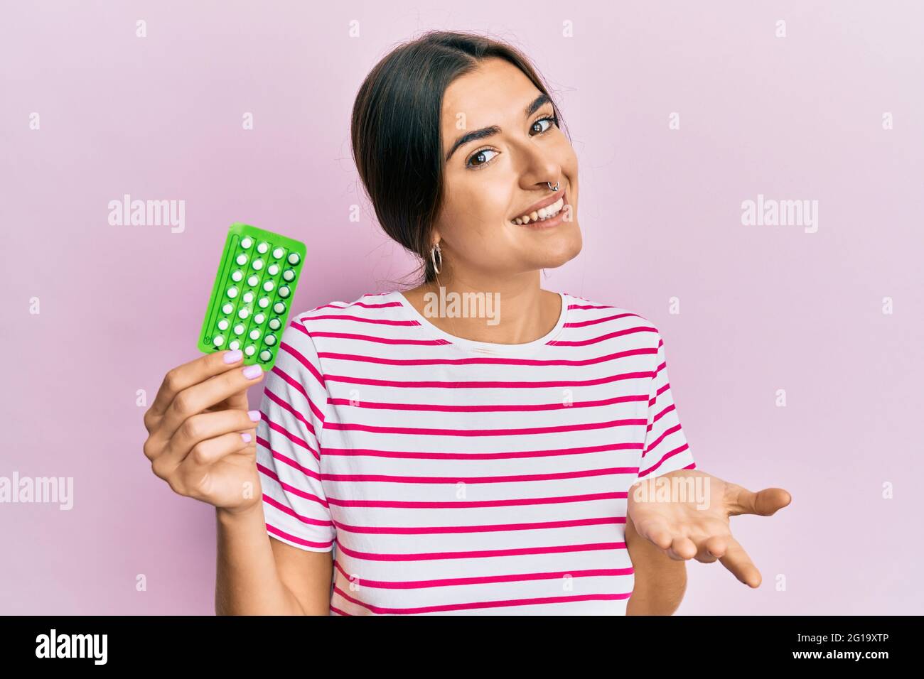 Young hispanic woman holding birth control pills celebrating ...