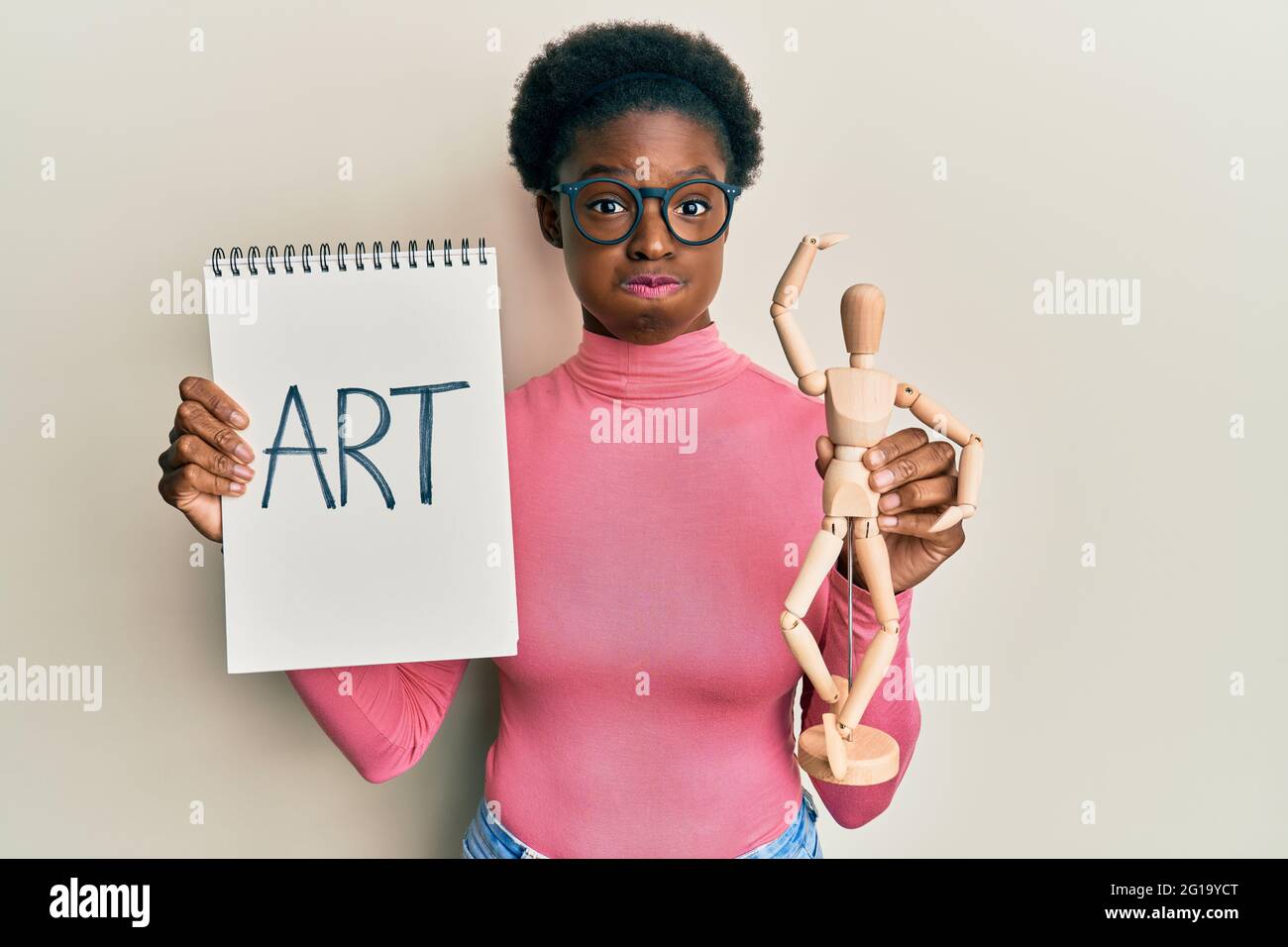 Young african american girl holding wooden manikin and art word on ...