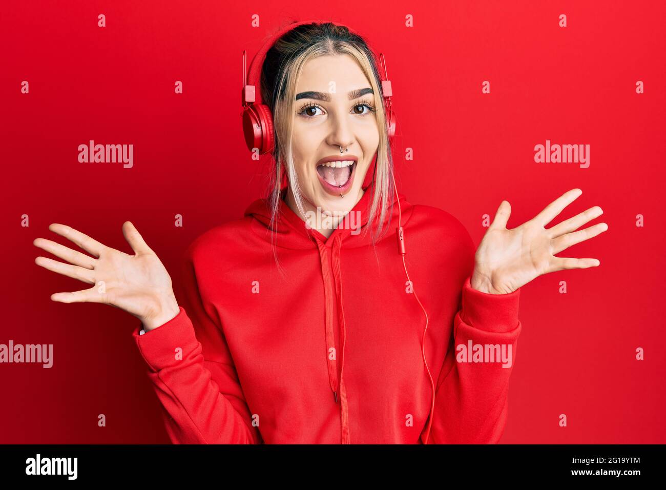 Young modern girl wearing gym clothes and using headphones celebrating ...