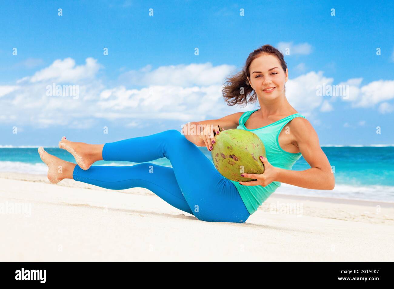 Young woman doing abdominal exercise on sea beach to keep fit and ...