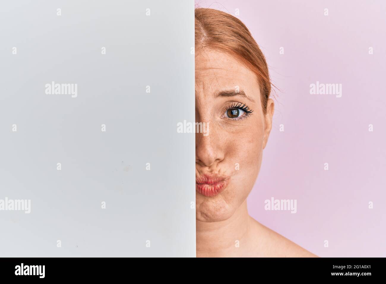 Young irish woman holding blank empty banner showing half face puffing ...