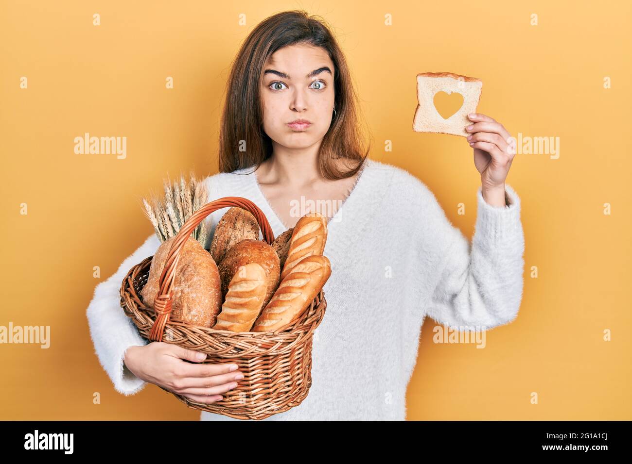 Young caucasian girl holding wicker basket with bread and loaf with ...