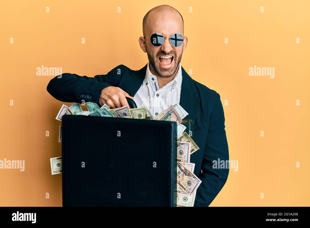 Young hispanic man holding briefcase with dollars smiling and laughing ...