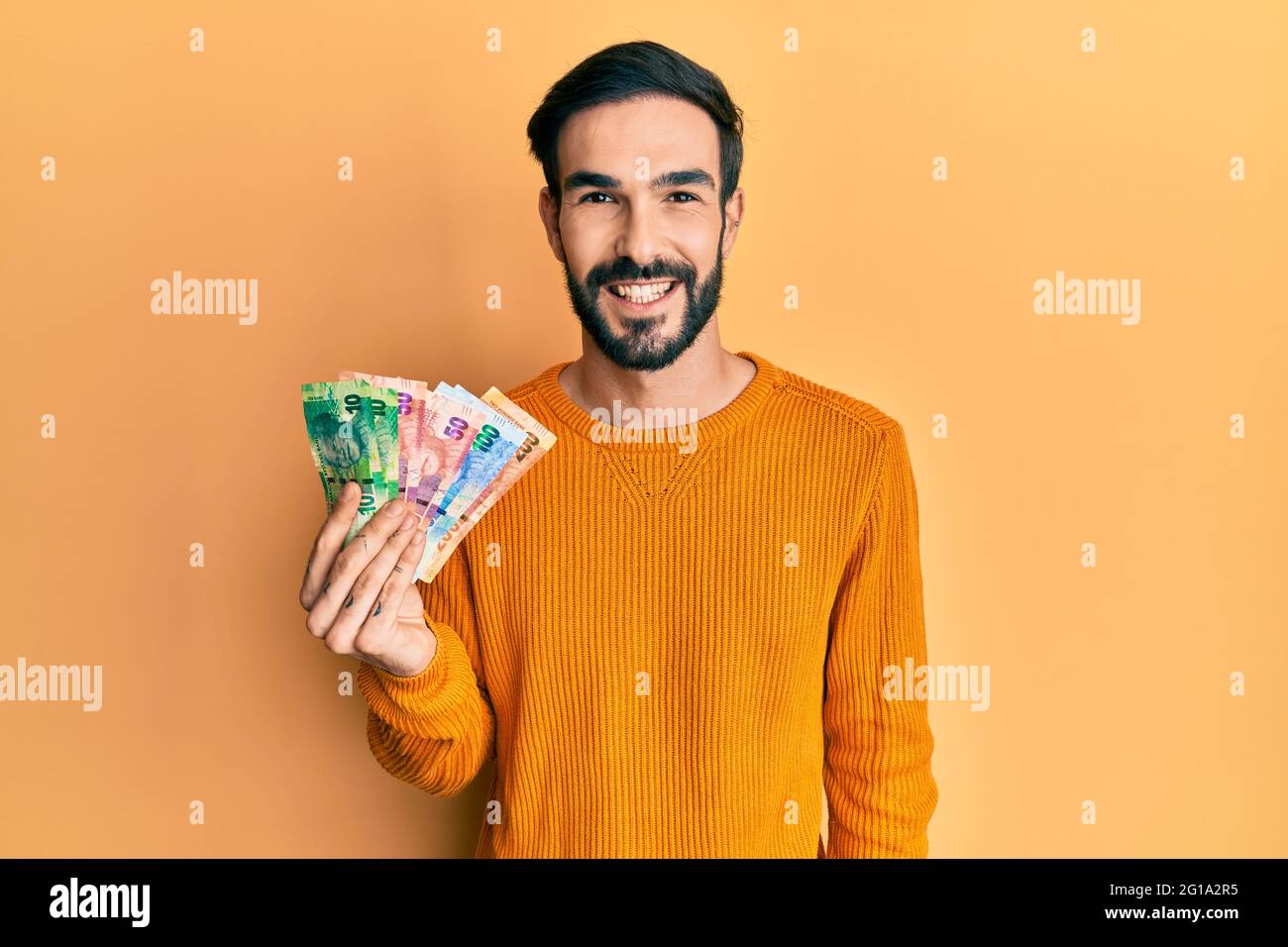 Young hispanic man holding south african rand banknotes looking ...