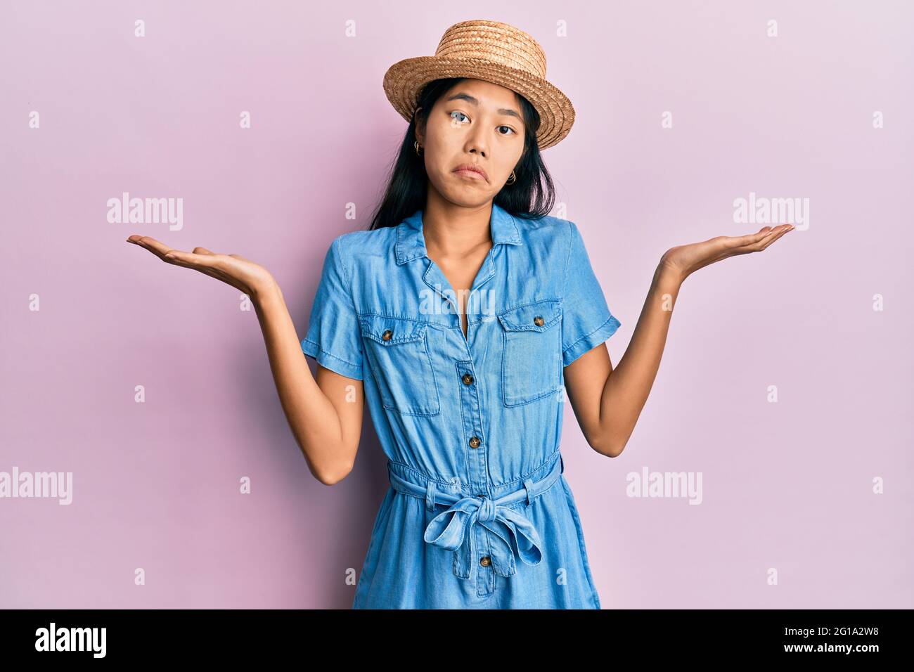 Young chinese woman wearing summer hat clueless and confused with open ...