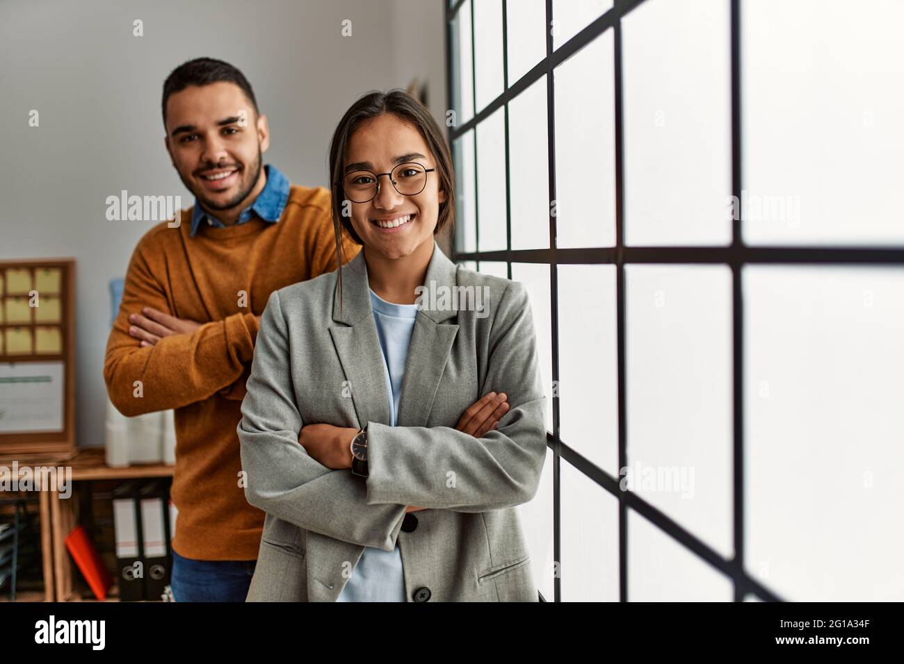 Two business workers standing with arms crossed gesture leaning on the ...