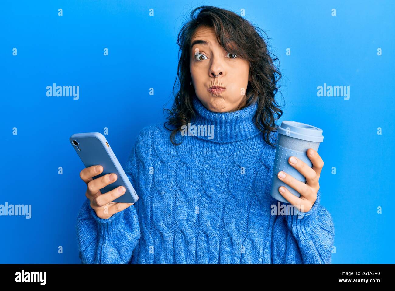 Young hispanic woman using smartphone and drinking a cup of coffee ...