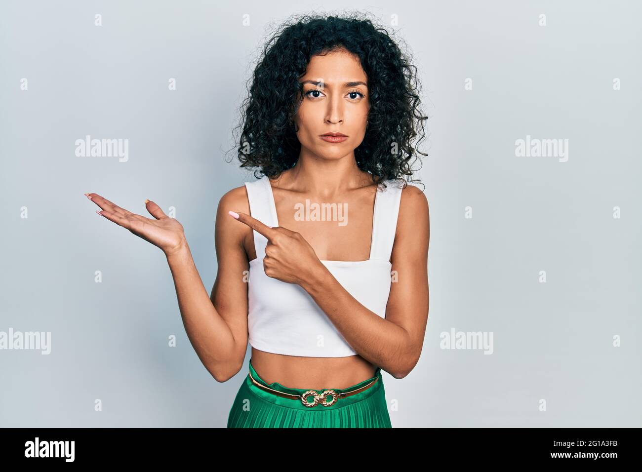 Young latin girl pointing open palm with finger depressed and worry for ...
