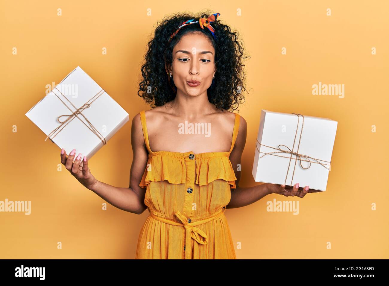 Young latin girl holding gifts making fish face with mouth and ...