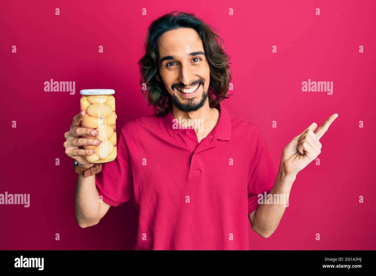 Young hispanic man holding bottle with boiled potatoes smiling happy ...