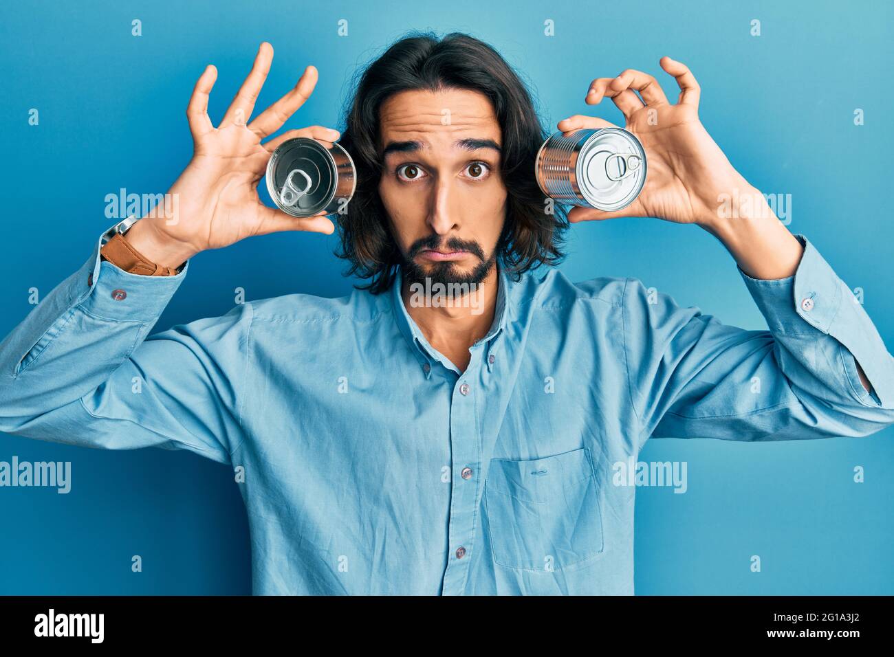 Young hispanic man holding canned food over eyes depressed and worry ...