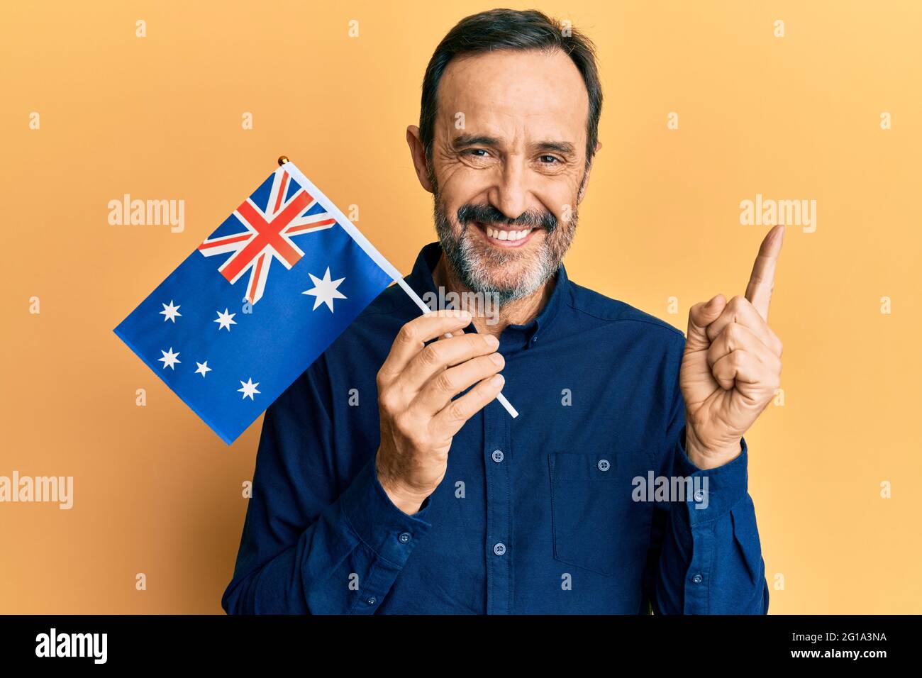 Middle age hispanic man holding australian flag smiling happy pointing ...