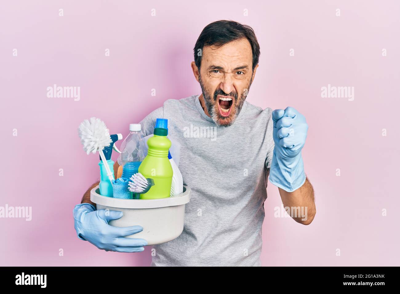 Middle age hispanic man holding cleaning products annoyed and ...