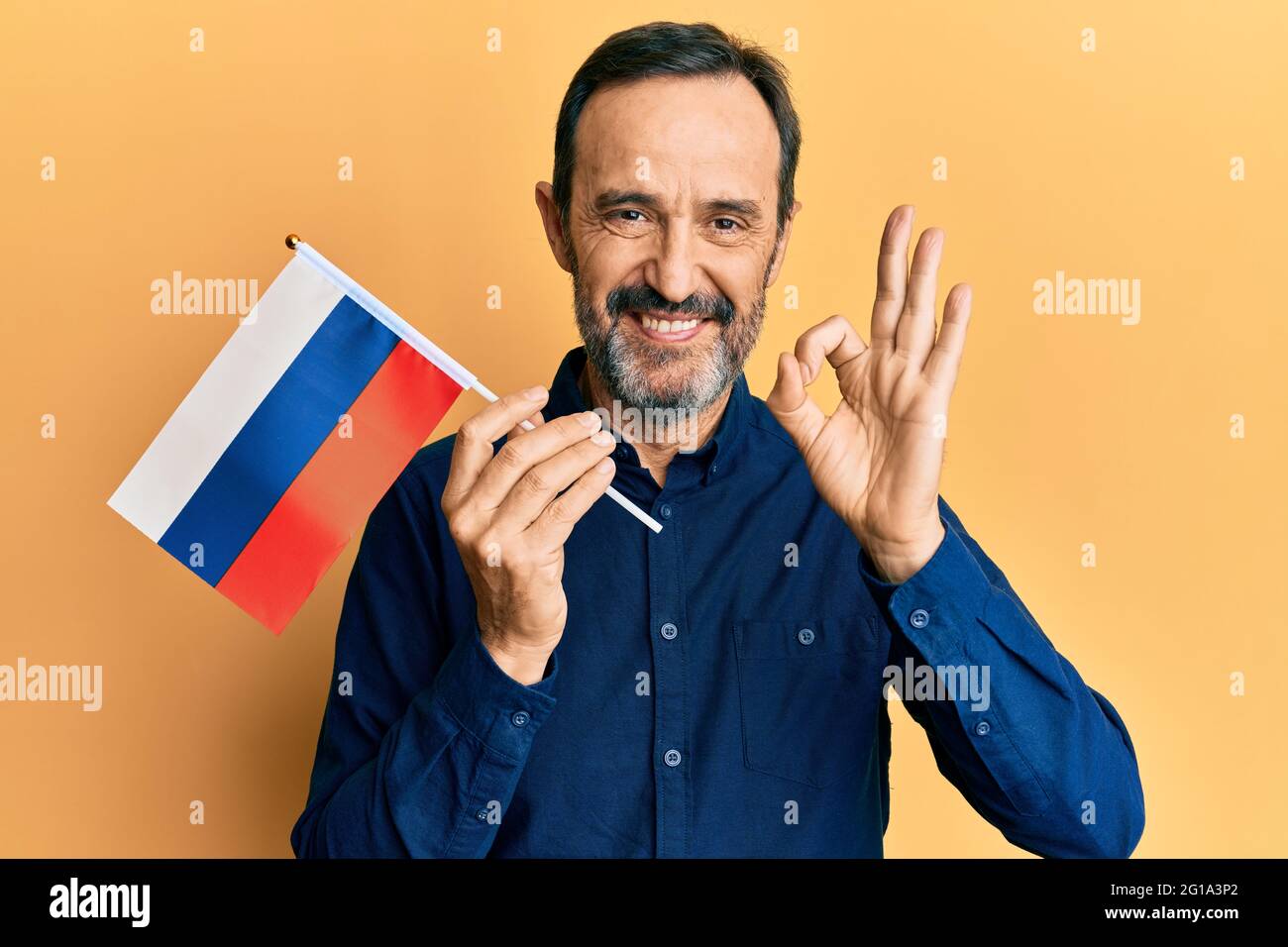 Middle age hispanic man holding russia flag doing ok sign with fingers ...