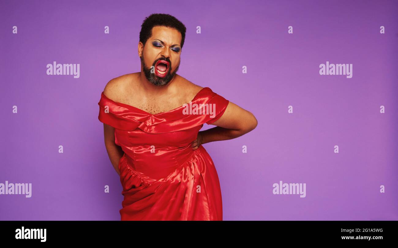 Gender fluid person with female dress performing on purple background ...