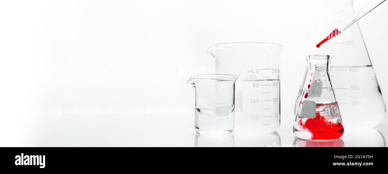 clear glass flask and beaker with orange drop solution in chemistry ...