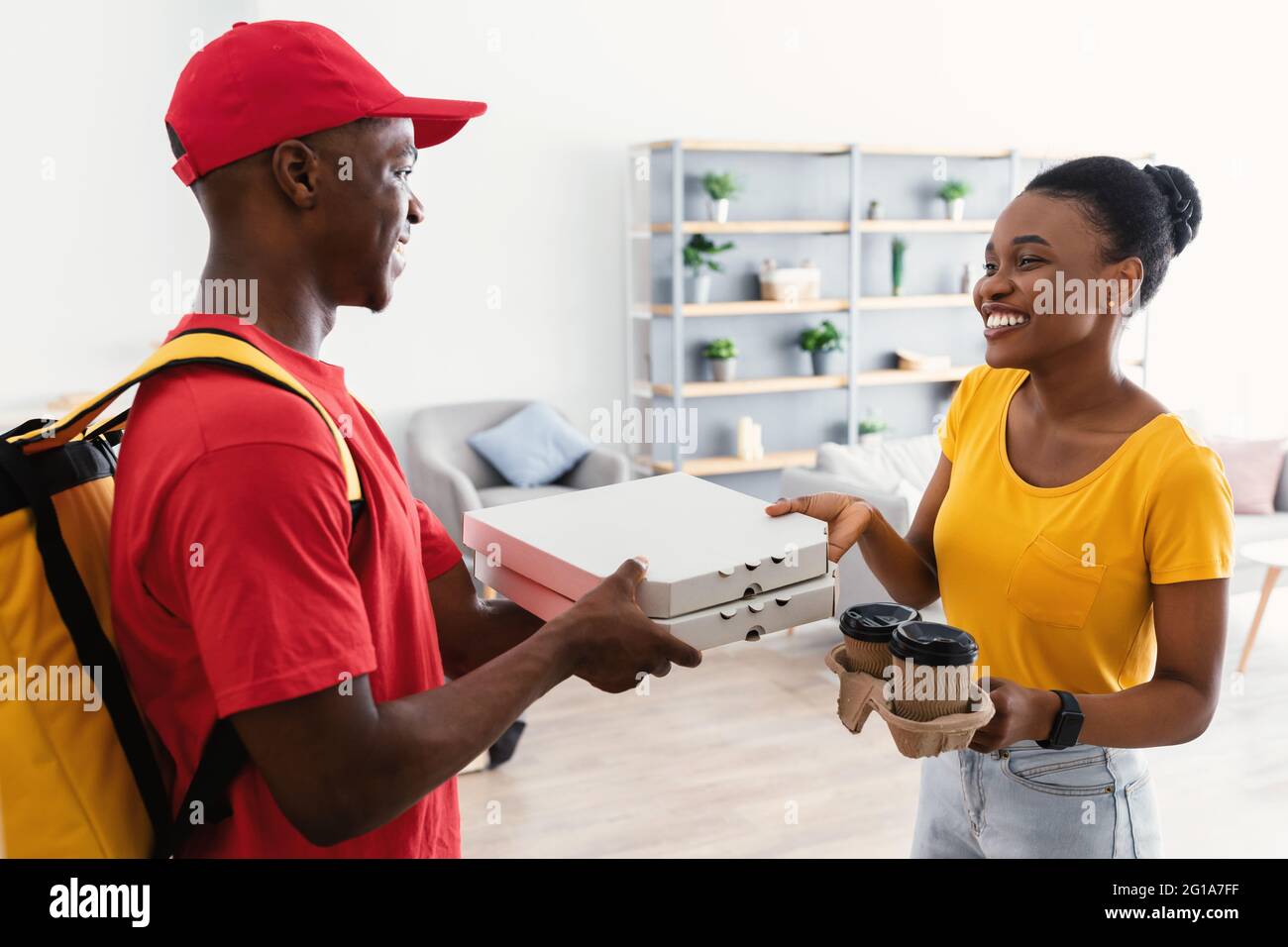 African Courier Guy Giving Pizza Box To Happy Female Indoor Stock Photo ...
