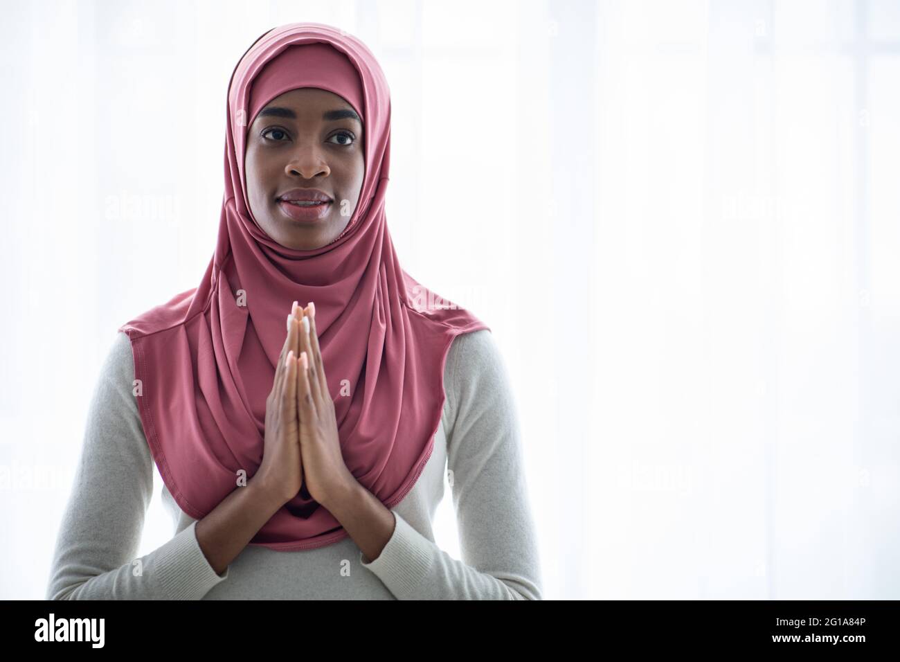 Portrait Of Black Islamic Lady In Hijab Praying Near Window At Home ...