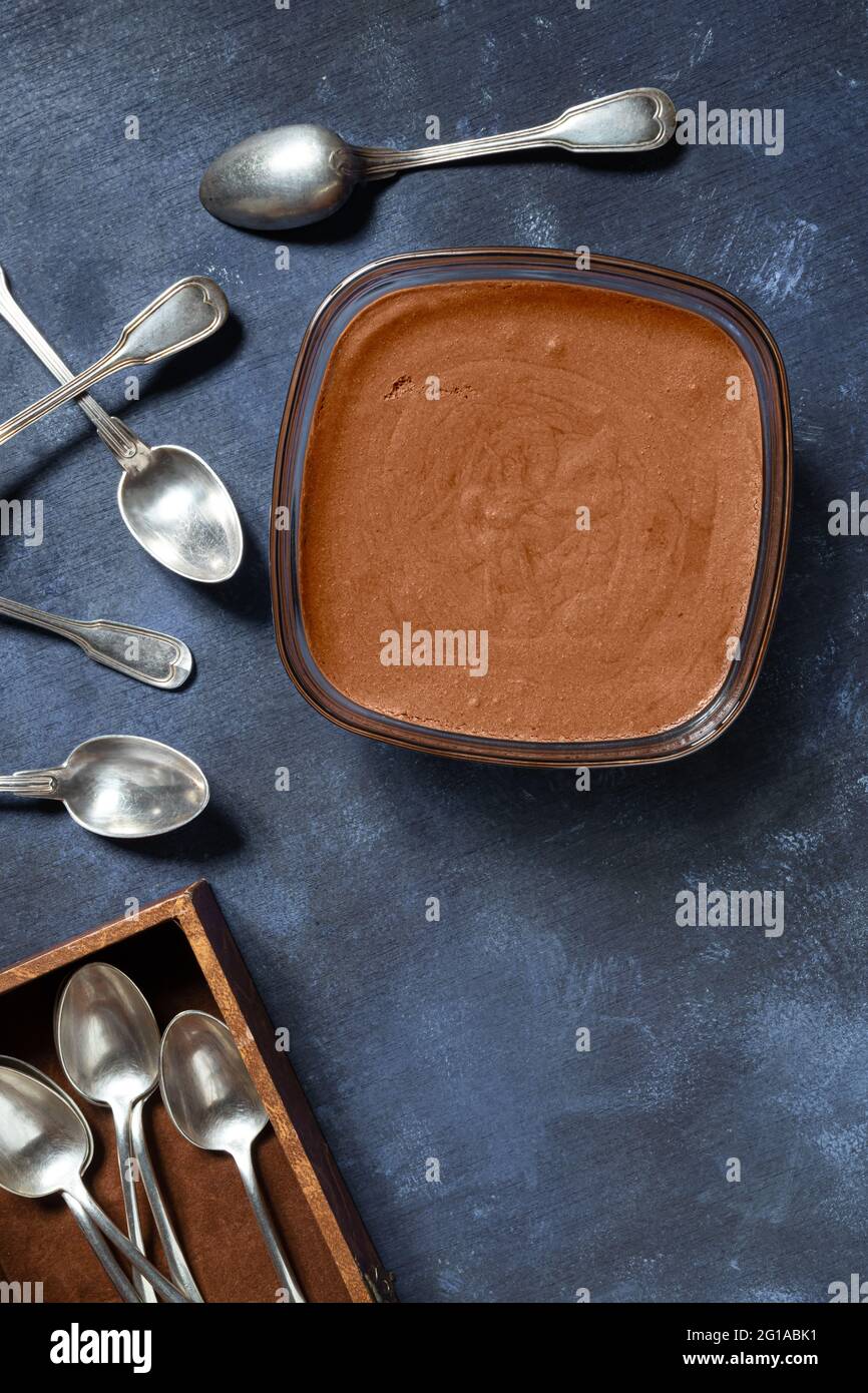 A bowl with traditional French chocolate mousse and silver spoons on ...