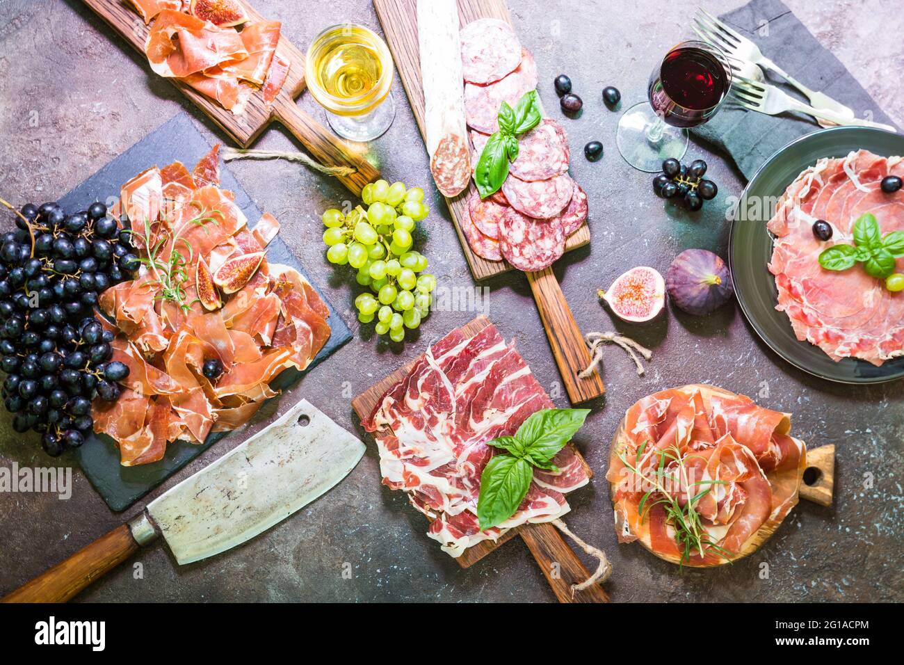 Different types jamon on cutting boardes with figs, grapes and wine ...