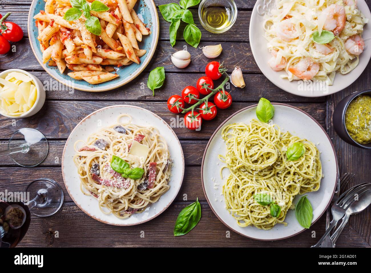 Several plates of pasta with different kinds of sauce over wooden ...