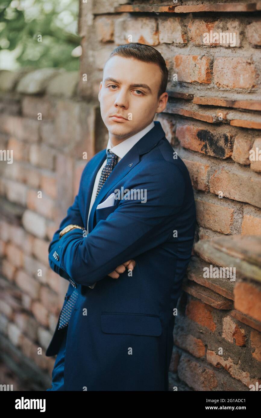 A handsome man in a suit standing near a brick wall Stock Photo - Alamy