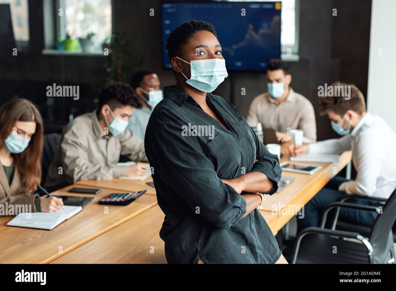 Young black businesswoman in mask sitting on desk and posing Stock ...