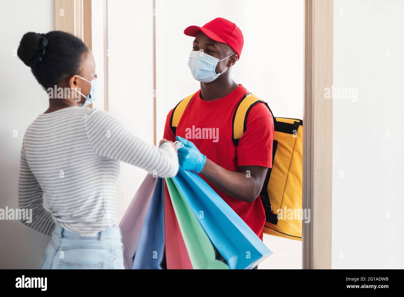 Black Courier Guy Giving Shopping Bags To Female Customer Indoors Stock ...