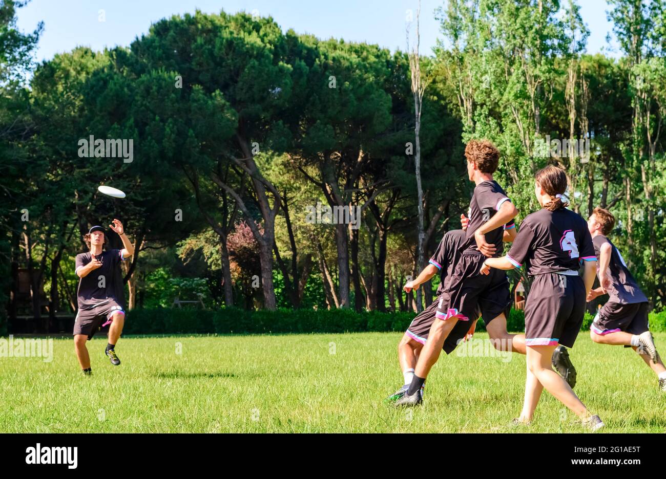 Group of young teenagers people in team wear playing a frisbee game in ...