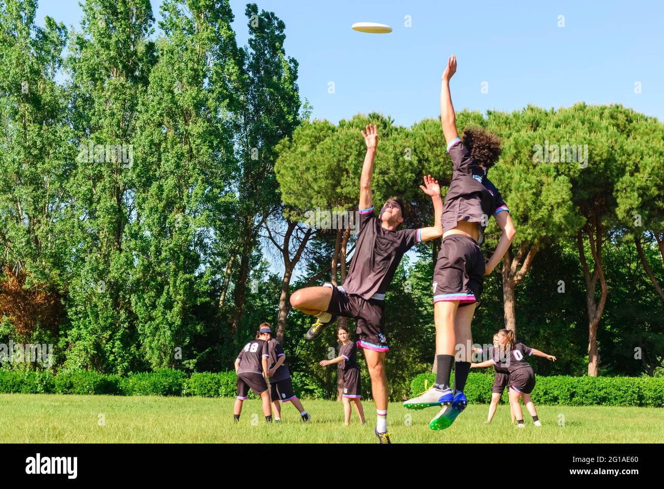 Group of young teenagers people in team wear playing a frisbee game in ...