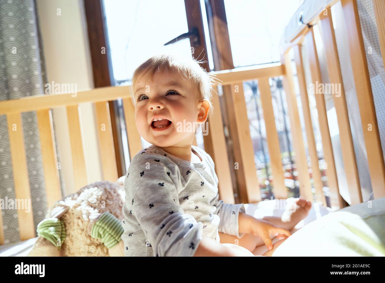 Smiling little child sitting on wooden bed Stock Photo - Alamy