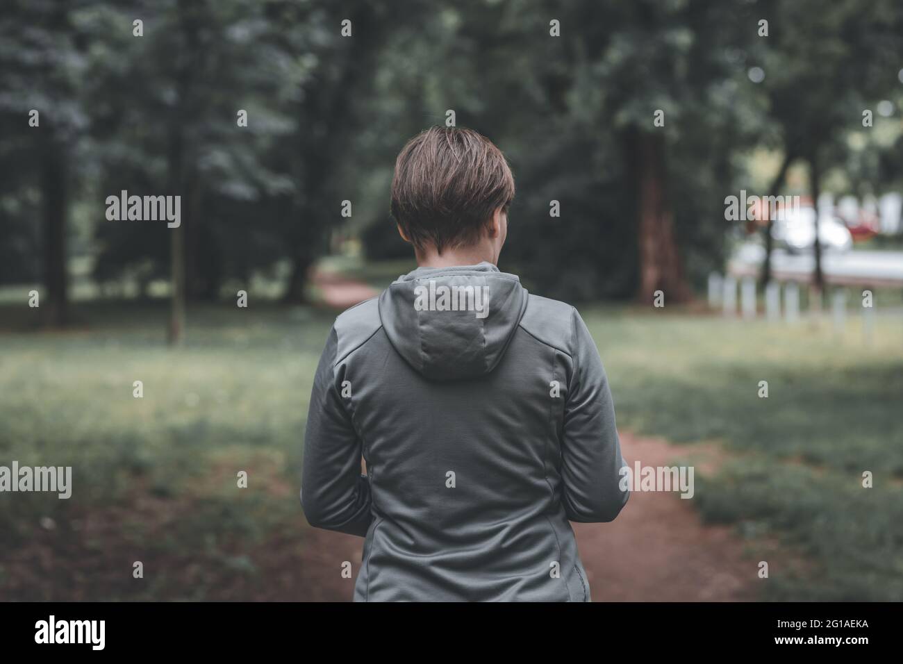 Rear view of adult female jogger in park ready for running on the track ...
