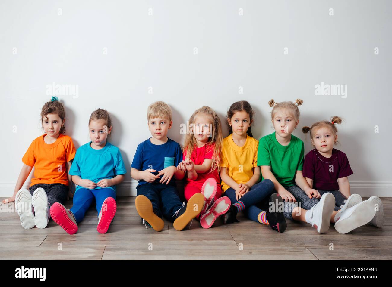 Cheerful children sitting on a floor near the wall Stock Photo - Alamy