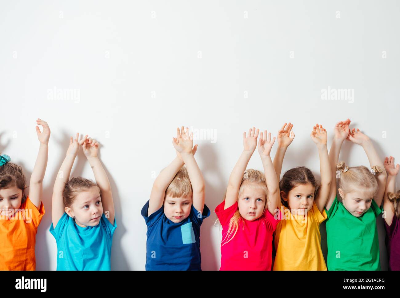 Children holding hands up on white wall background Stock Photo - Alamy