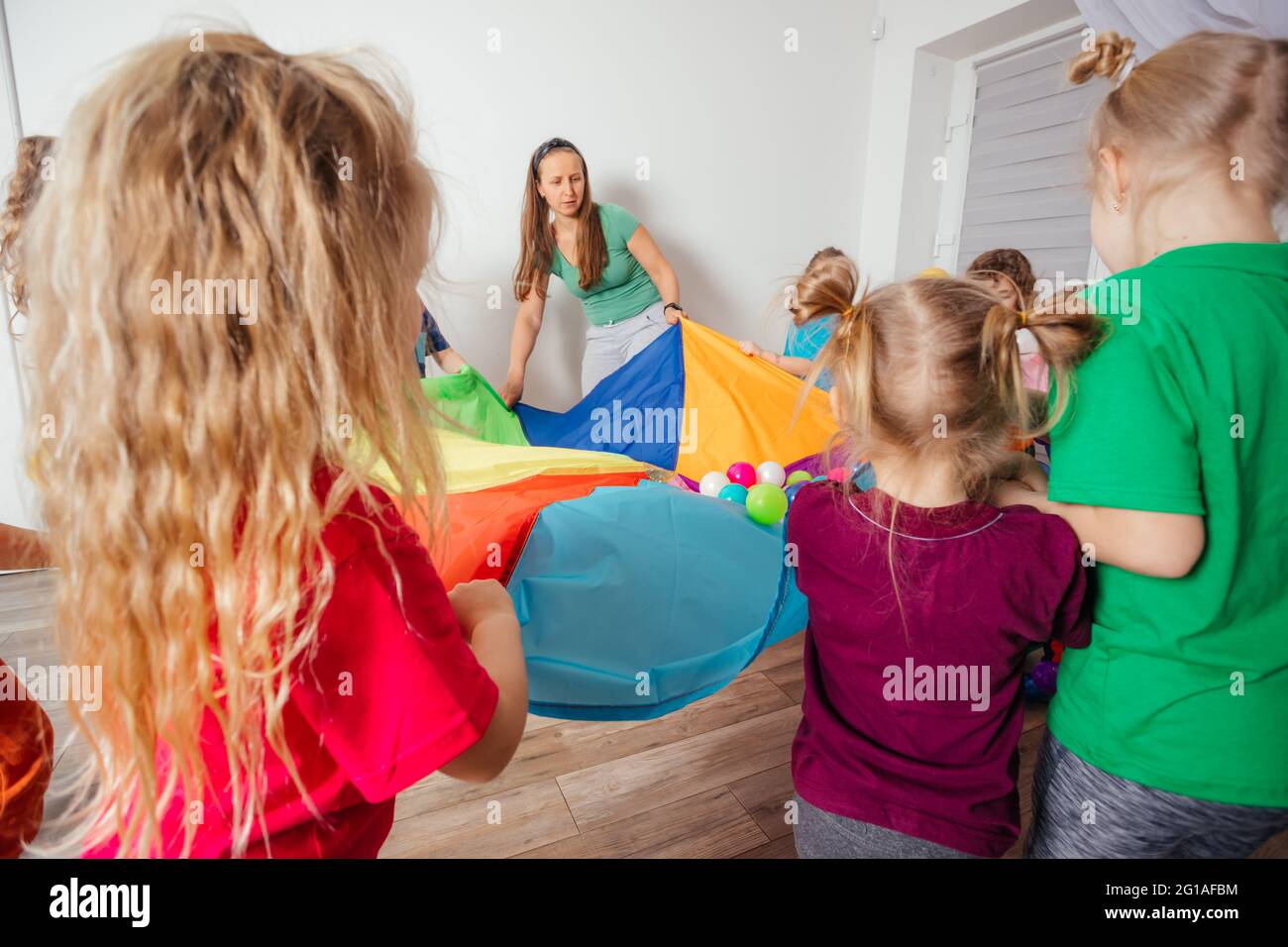 Teacher and kindergarten kids playing with colorful parachute Stock ...